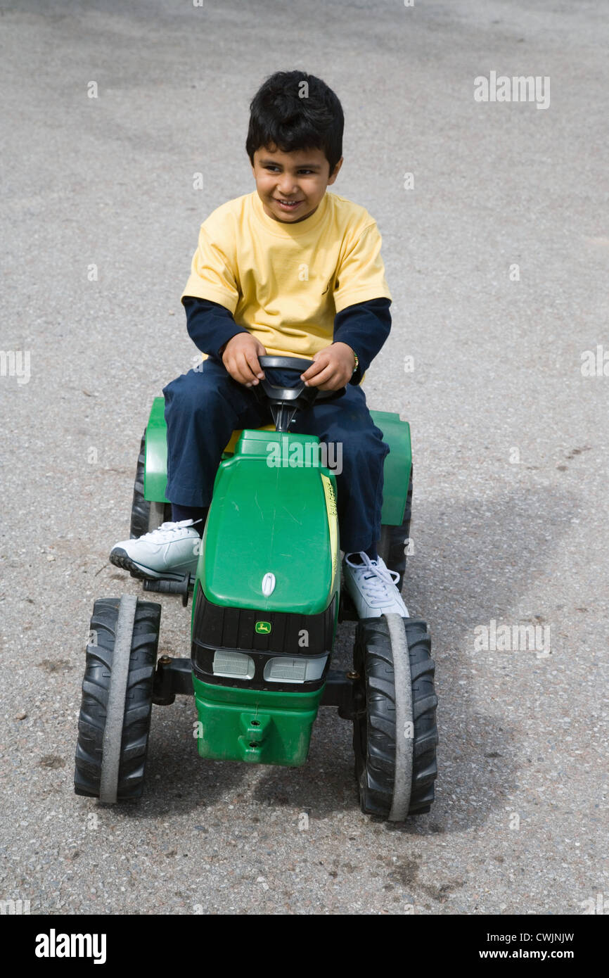 Young boy riding on a toy tractor Stock Photo - Alamy