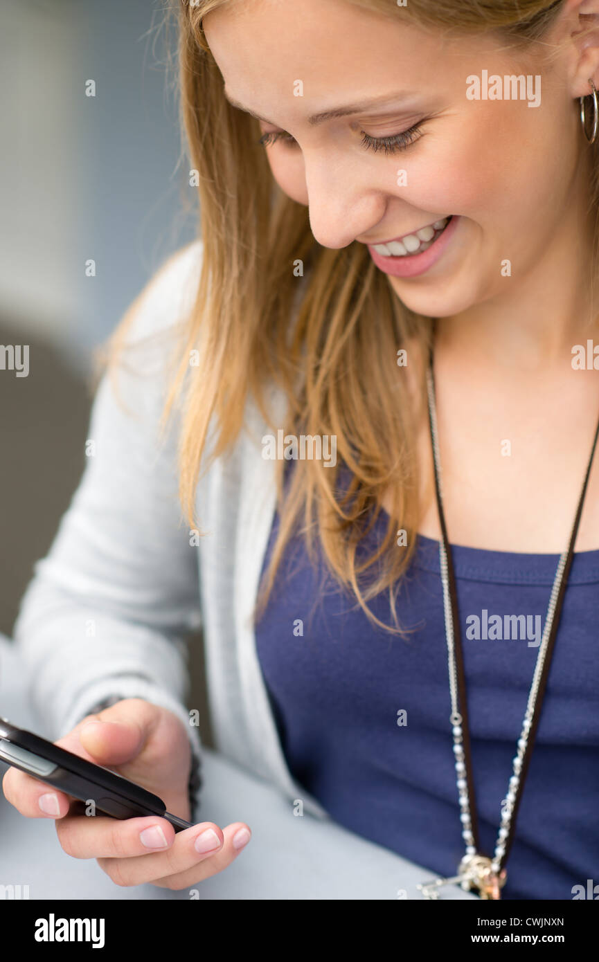Smiling teenage woman reading text message on cellphone Stock Photo - Alamy