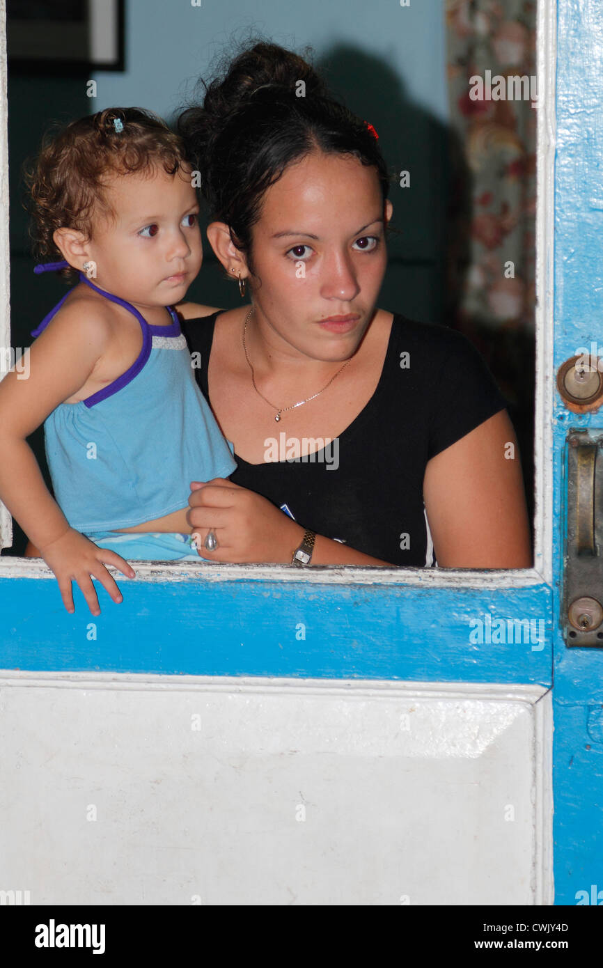 Young Cuban mother and her daughter looking at camera from the door ...