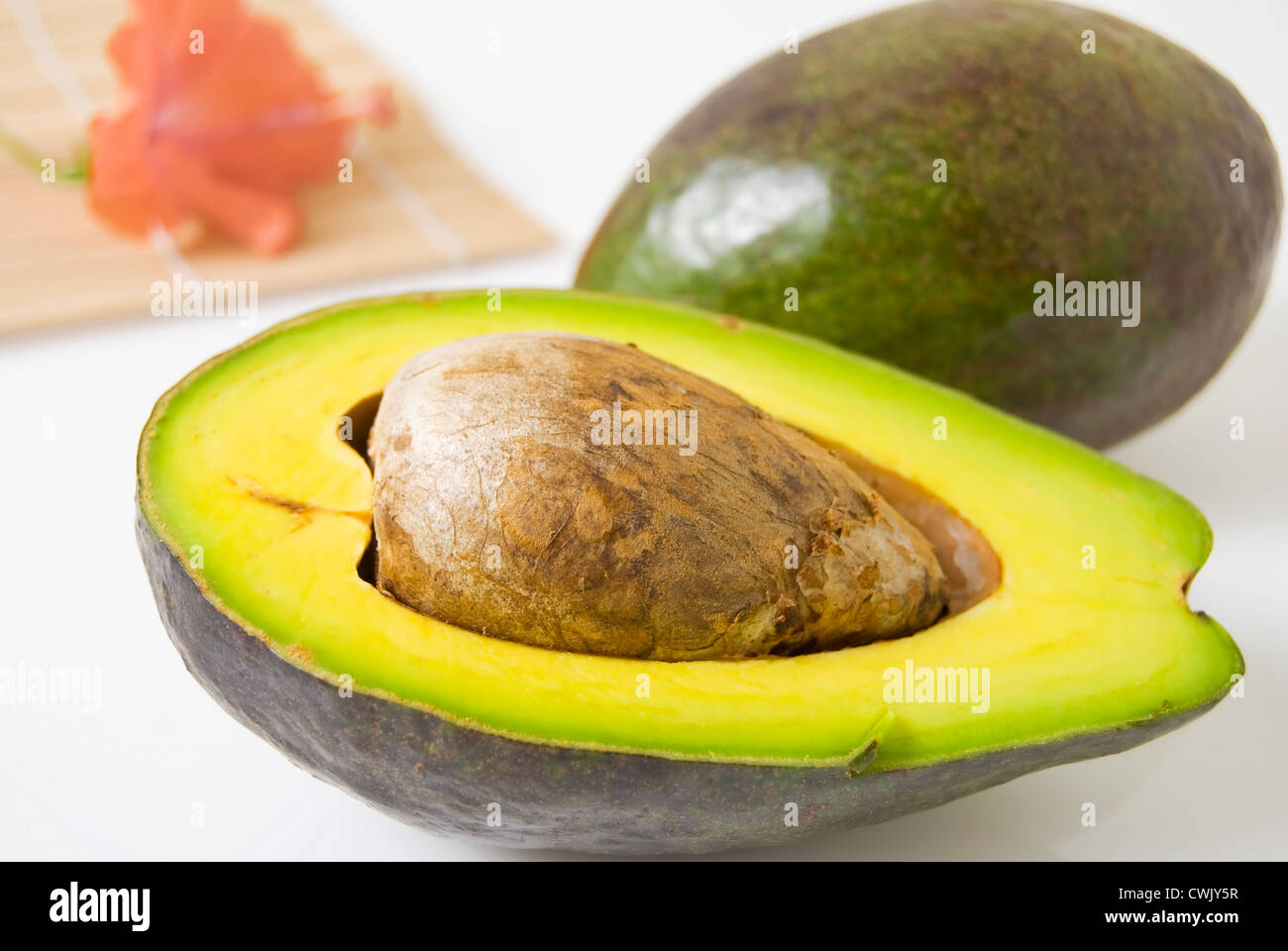 Avocado and red flower on wooden place mat Stock Photo - Alamy