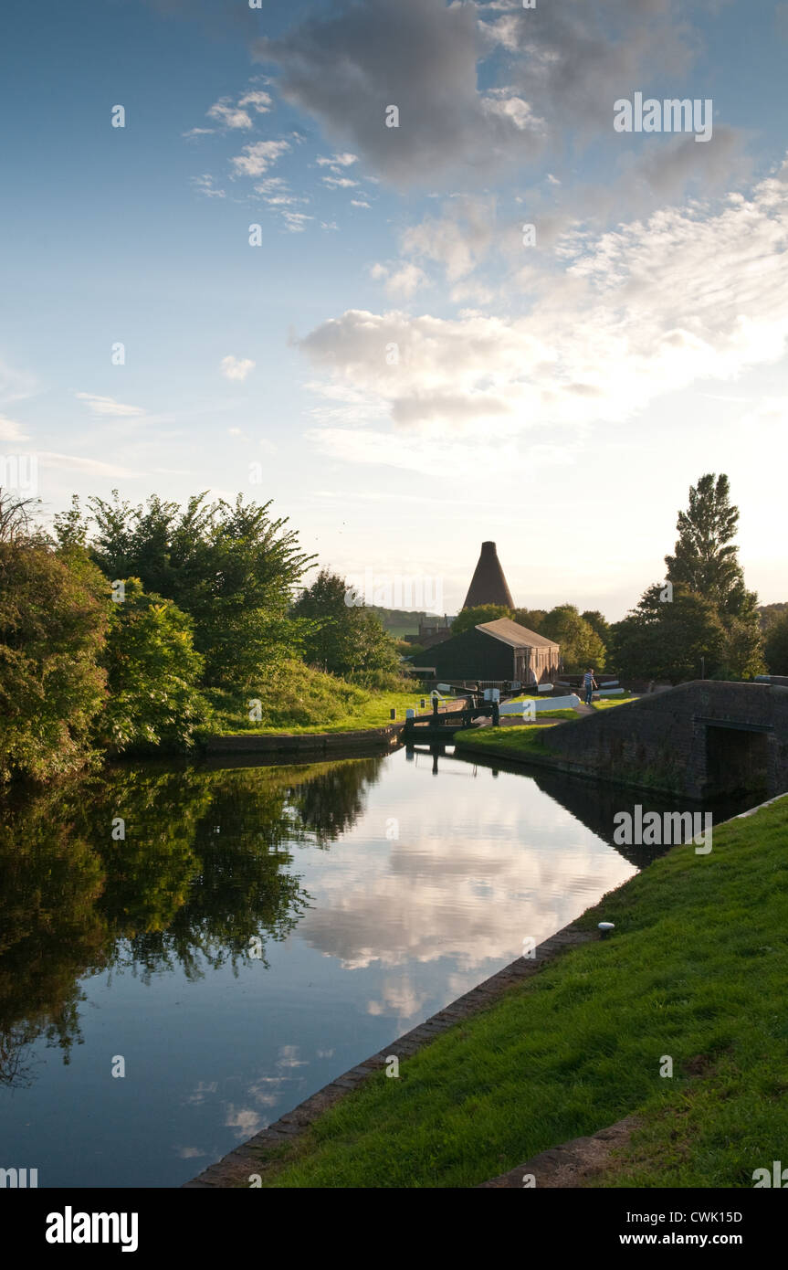 Late summer sun and trees reflected in a canal basin and in front of ...