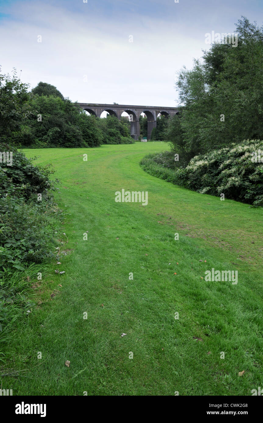 View of Stourbridge viaduct with a large sweep of grass and hedges ...