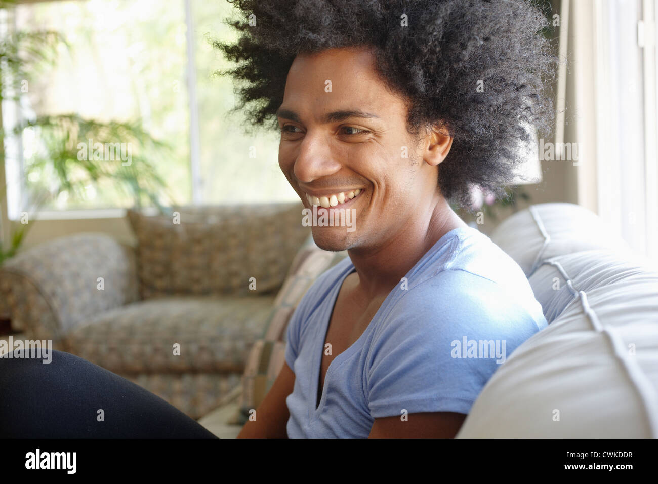 Smiling man sitting on sofa in living room Stock Photo - Alamy