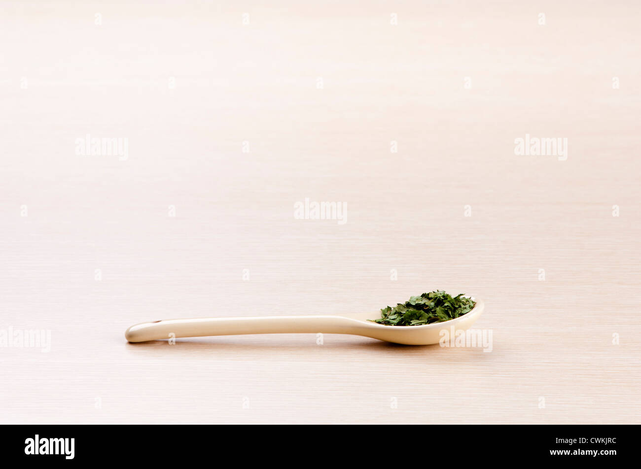 Coriander in a spoon over a blured wooden background with copy space ...