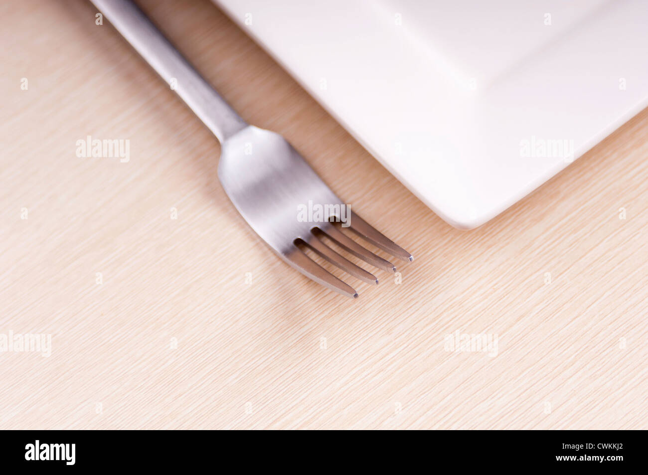 Modern fork and plate on wooden table Stock Photo - Alamy