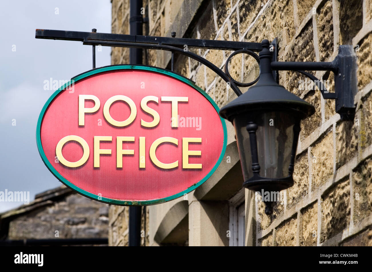 traditional post office sign and old style lamp on stone walled ...