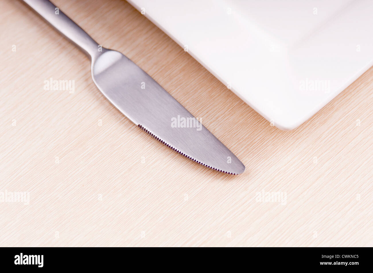 Modern knife and plate on wooden table Stock Photo - Alamy