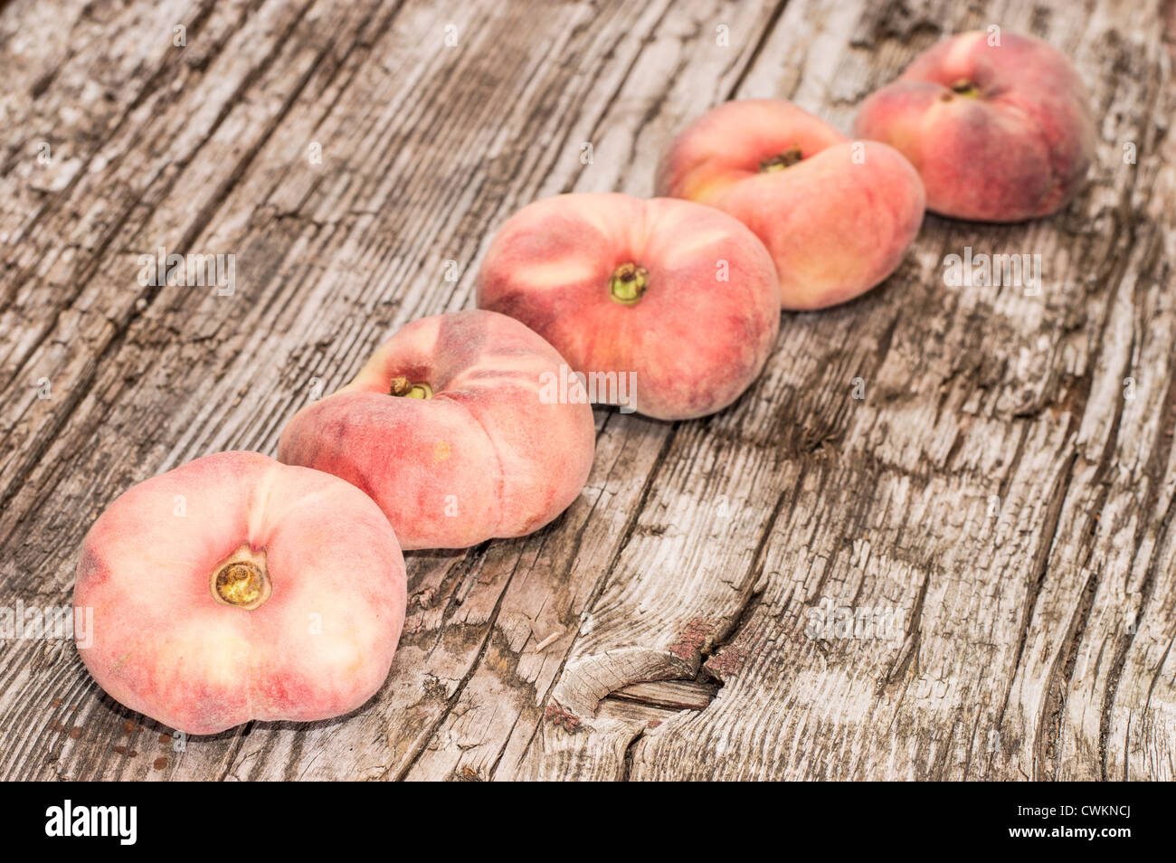 Wild Peaches in a row on wooden background Stock Photo - Alamy