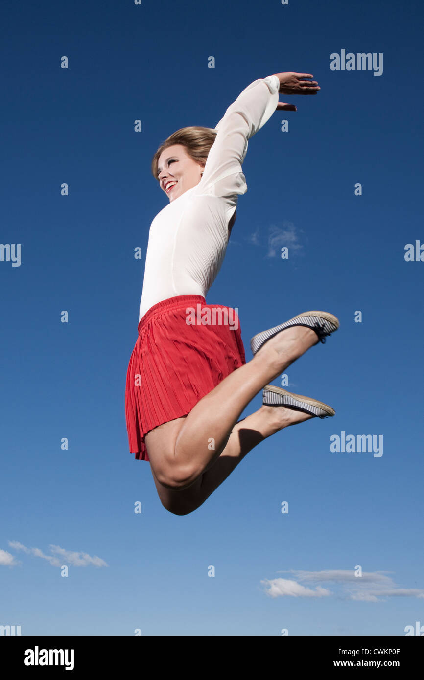 happily jumping woman on a bright blue sky Stock Photo - Alamy