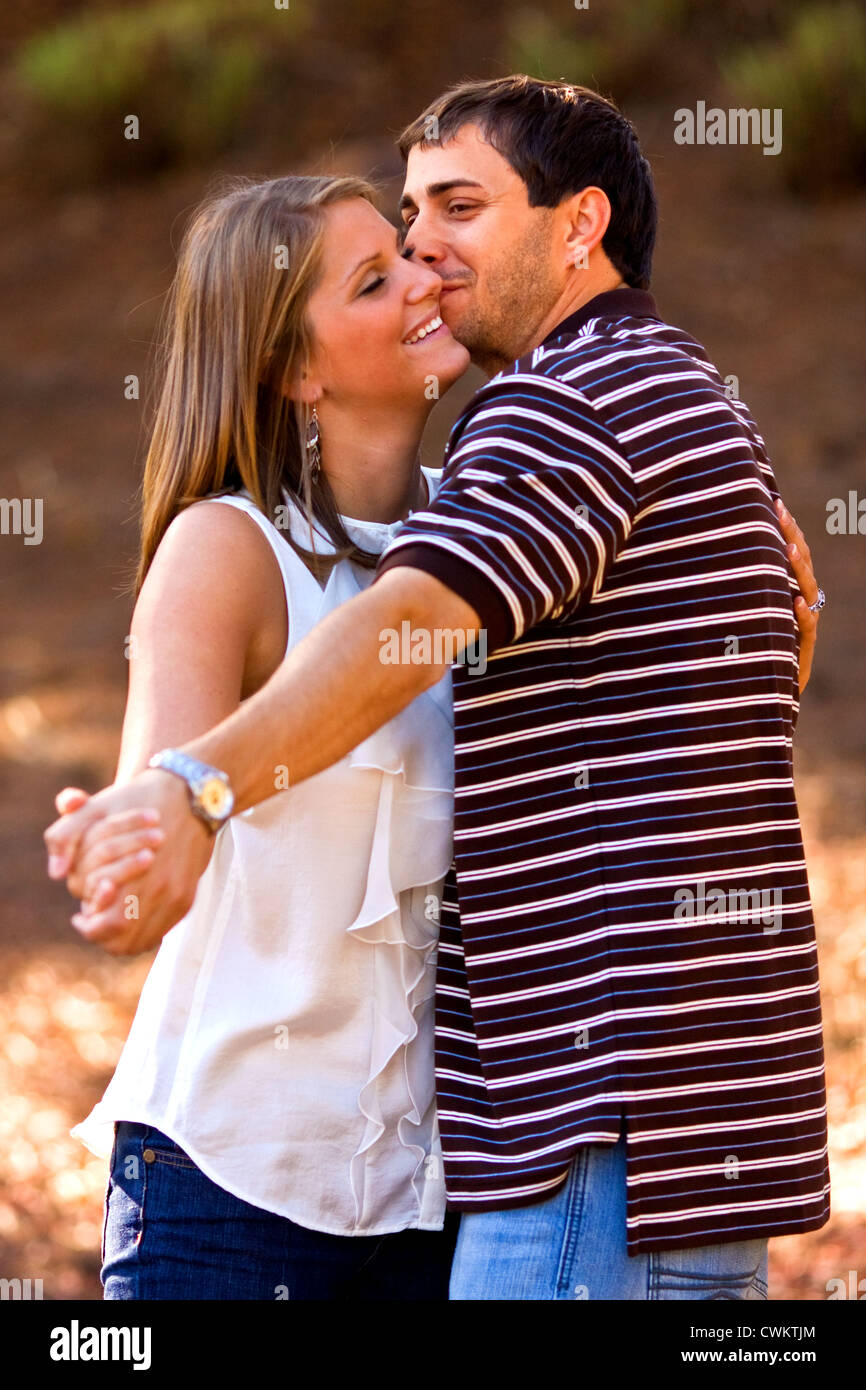 A young couple in love strikes a mock dance pose as they playfully ...