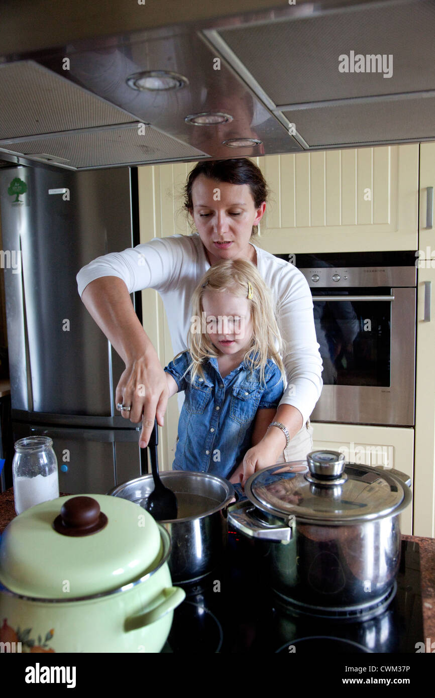 Polish mom helping daughter age 4 cook and stir at stove. Zawady ...