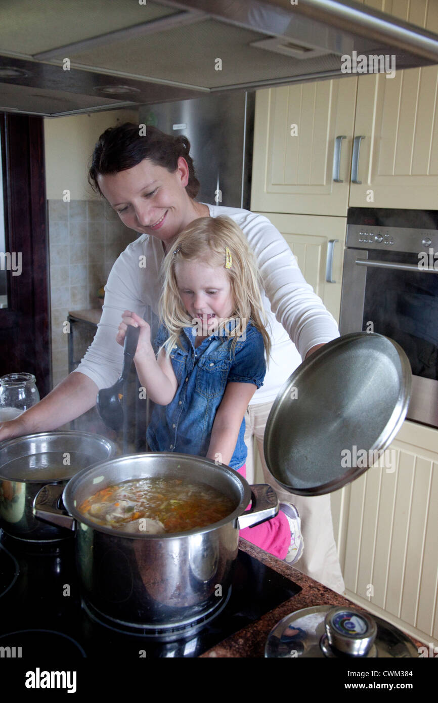 Polish mom helping daughter age 4 cook at stove making soup. Zawady ...