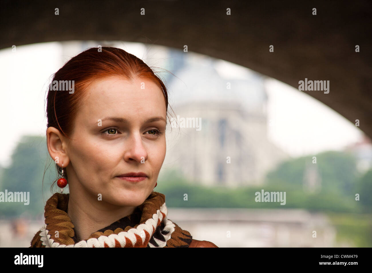 A red-haired woman standing under an arch with the Notre Dame Cathedral ...