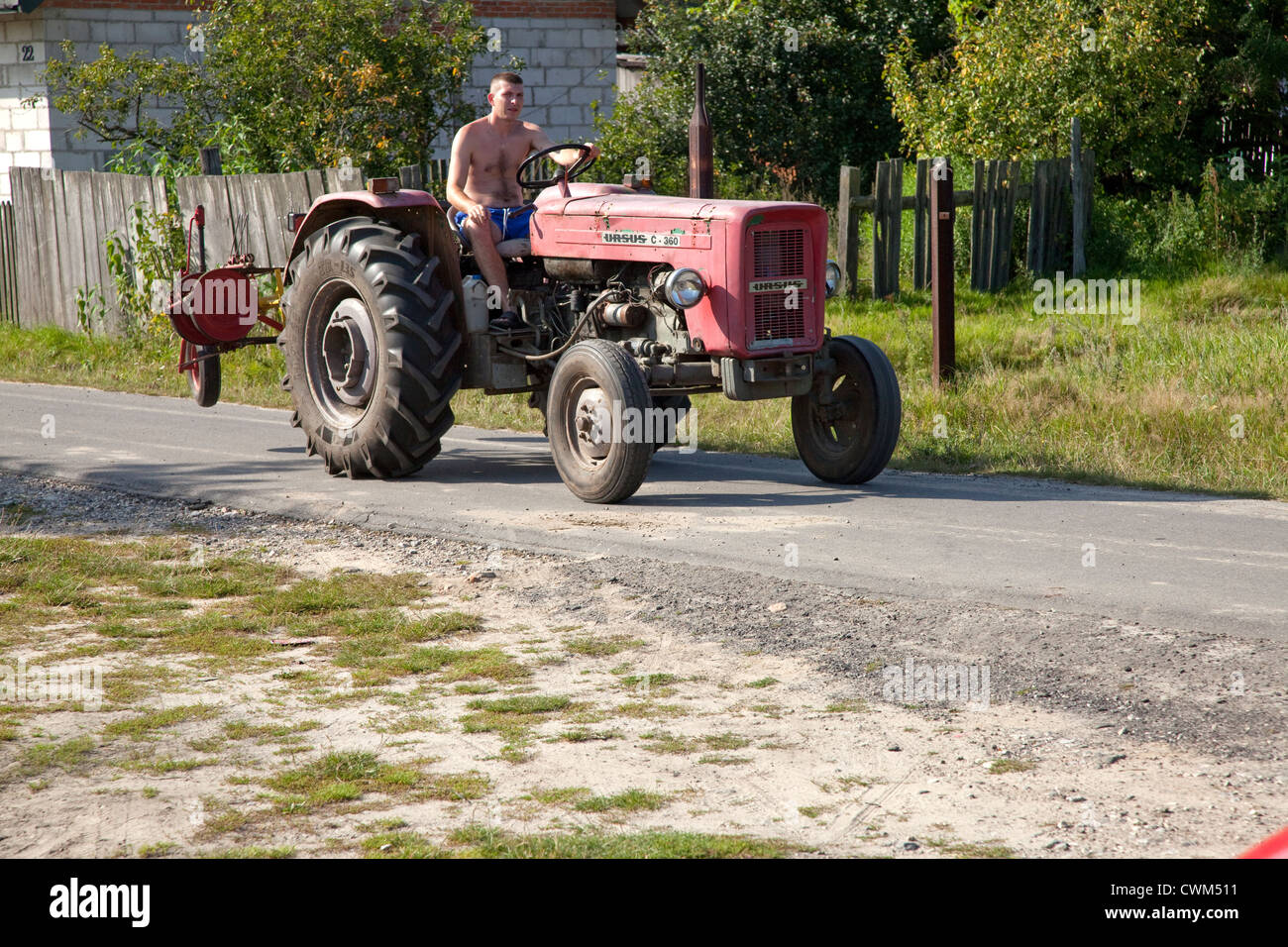 Polish man driving tractor down village lane age 22. Mala Wola Central ...