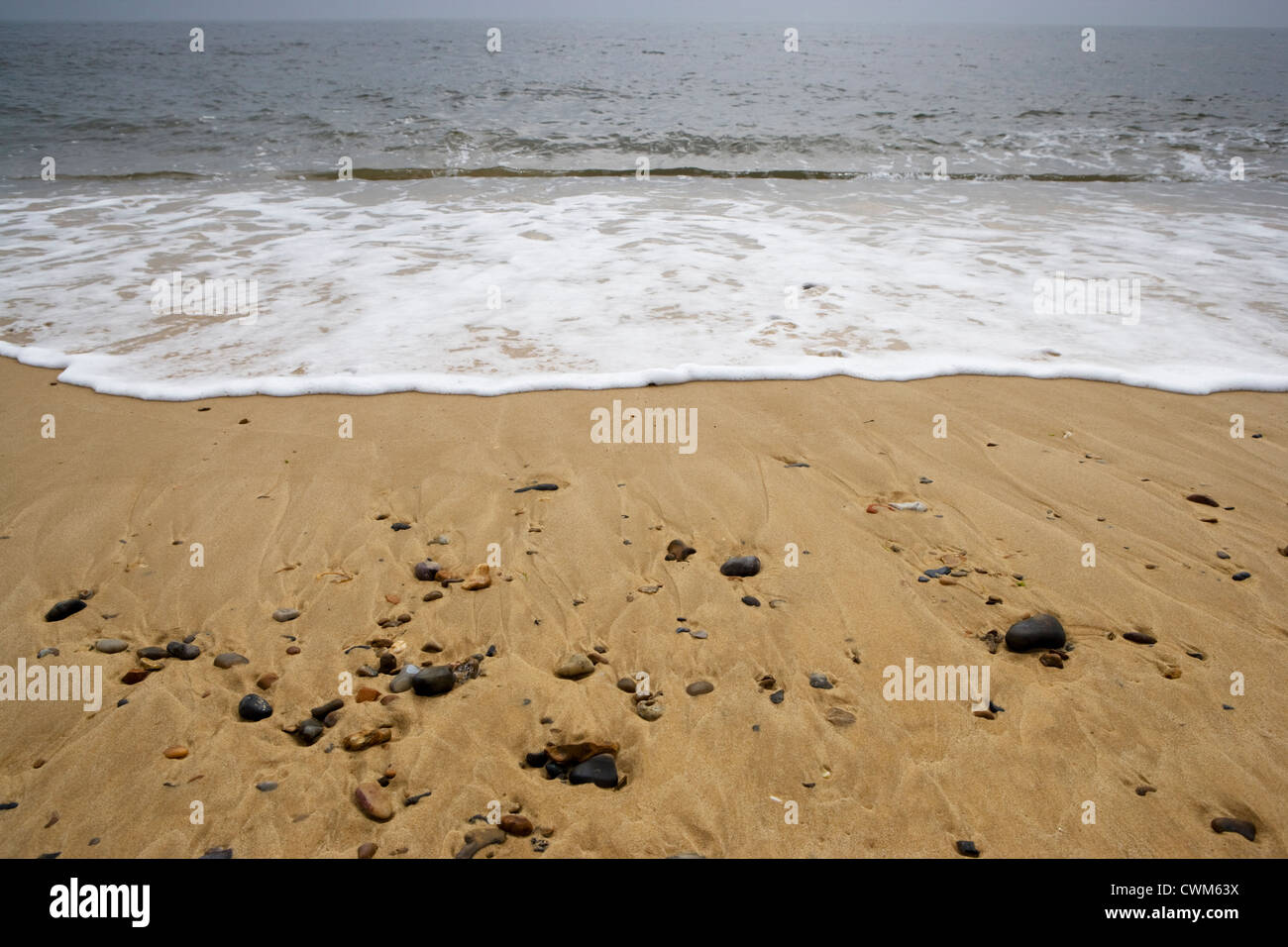 Low angle view of waves breaking on the shoreline on a sandy beach ...