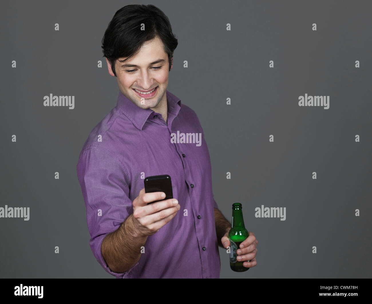 Young man with beer bottle and mobile phone, smiling Stock Photo - Alamy