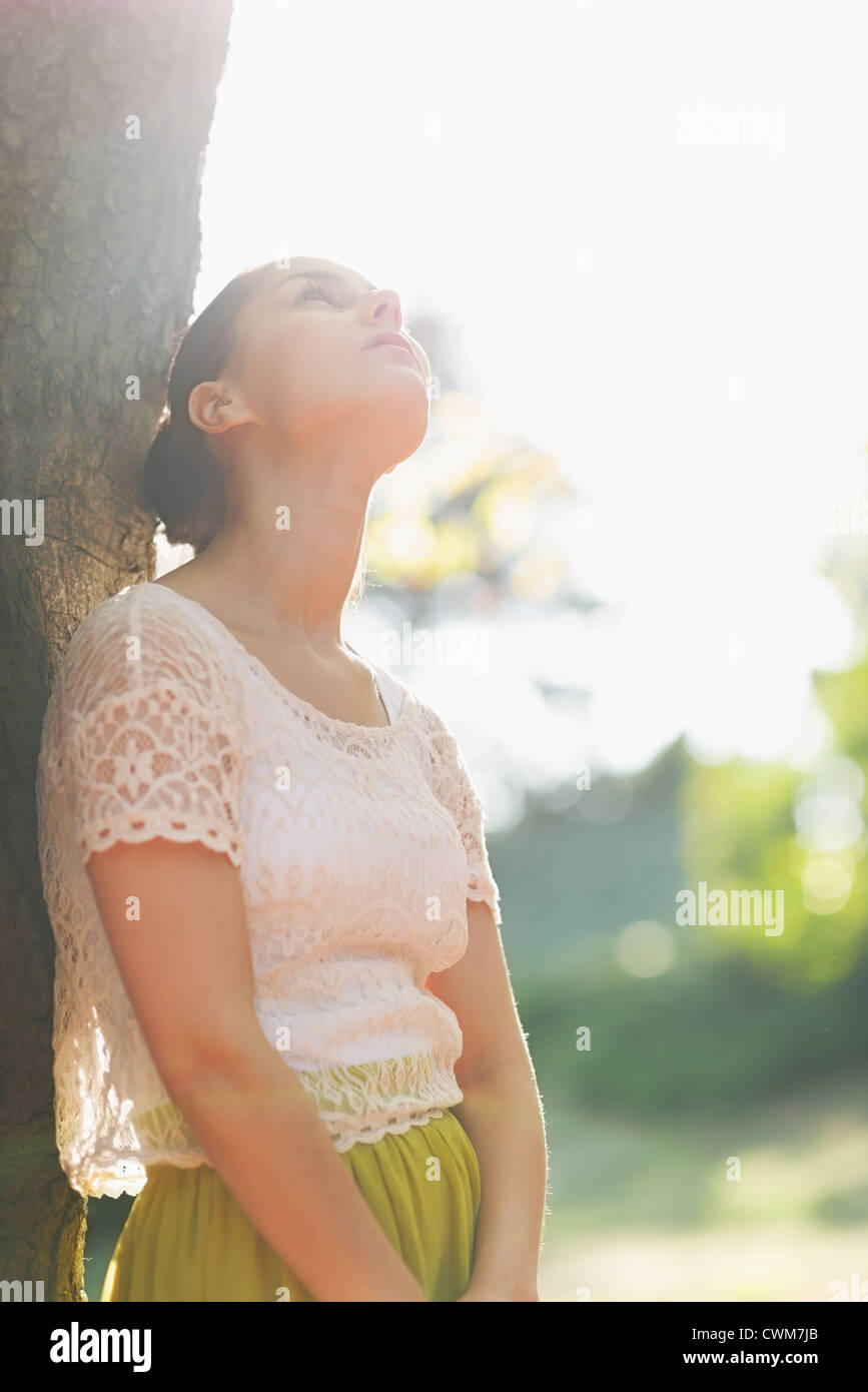 Thoughtful girl lean against tree Stock Photo - Alamy