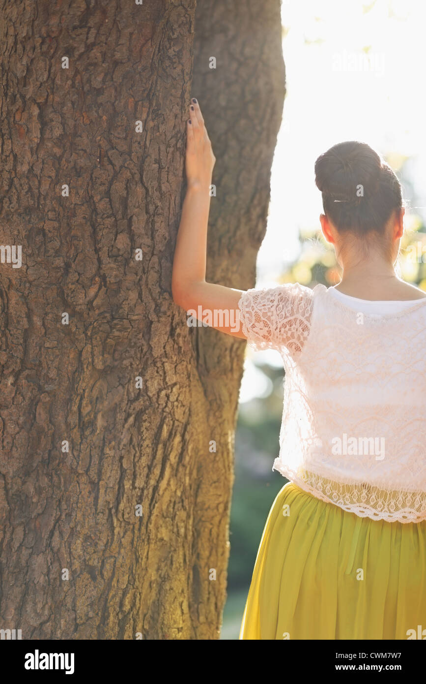 Young woman lean against tree. Rear view Stock Photo - Alamy
