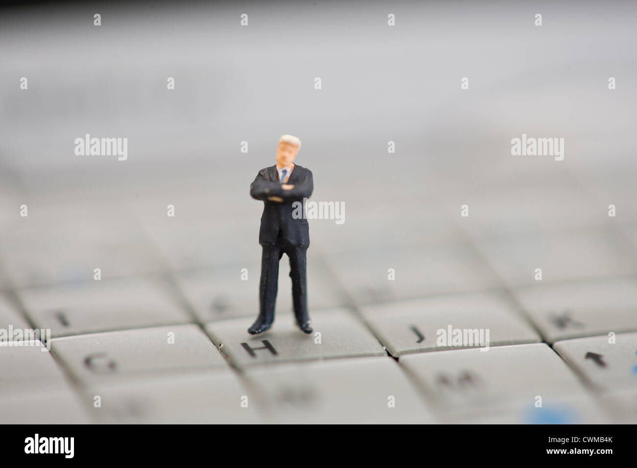 Figurine standing on computer keyboard Stock Photo - Alamy