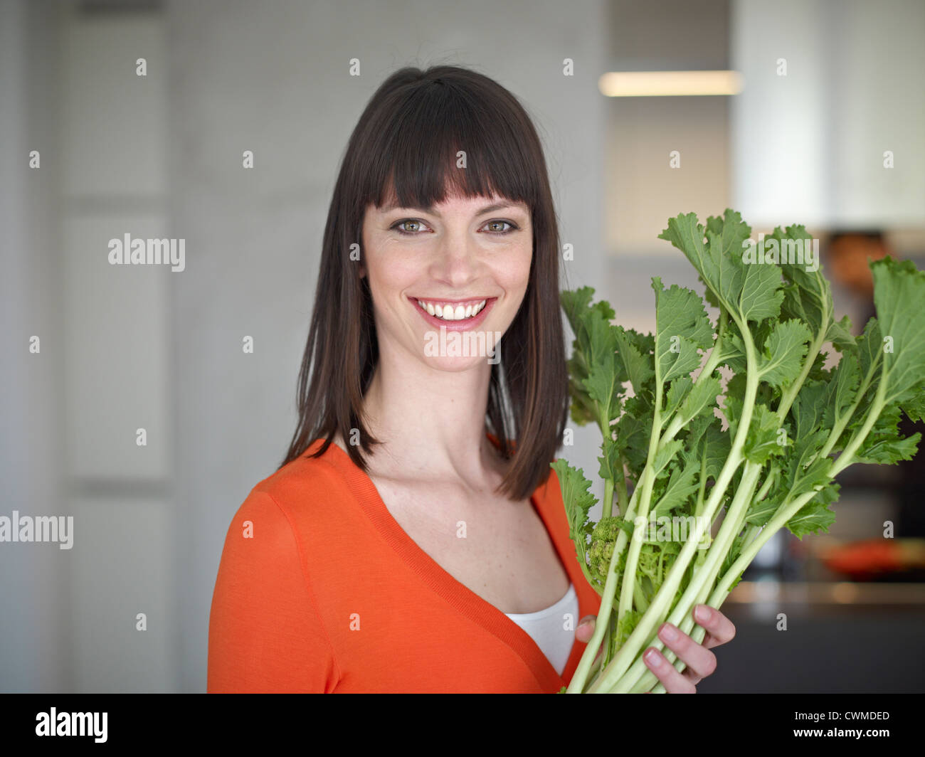 Germany, Cologne, Mid adult woman holding vegetable, smiling, portrait ...