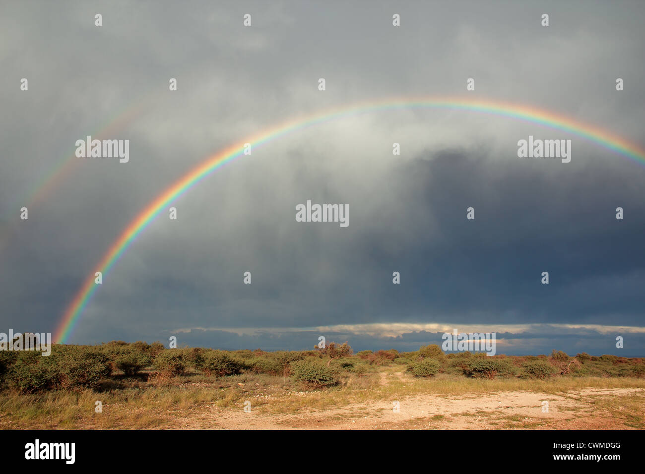 Rural landscape with a colorful rainbow and heavy rain clouds, southern ...