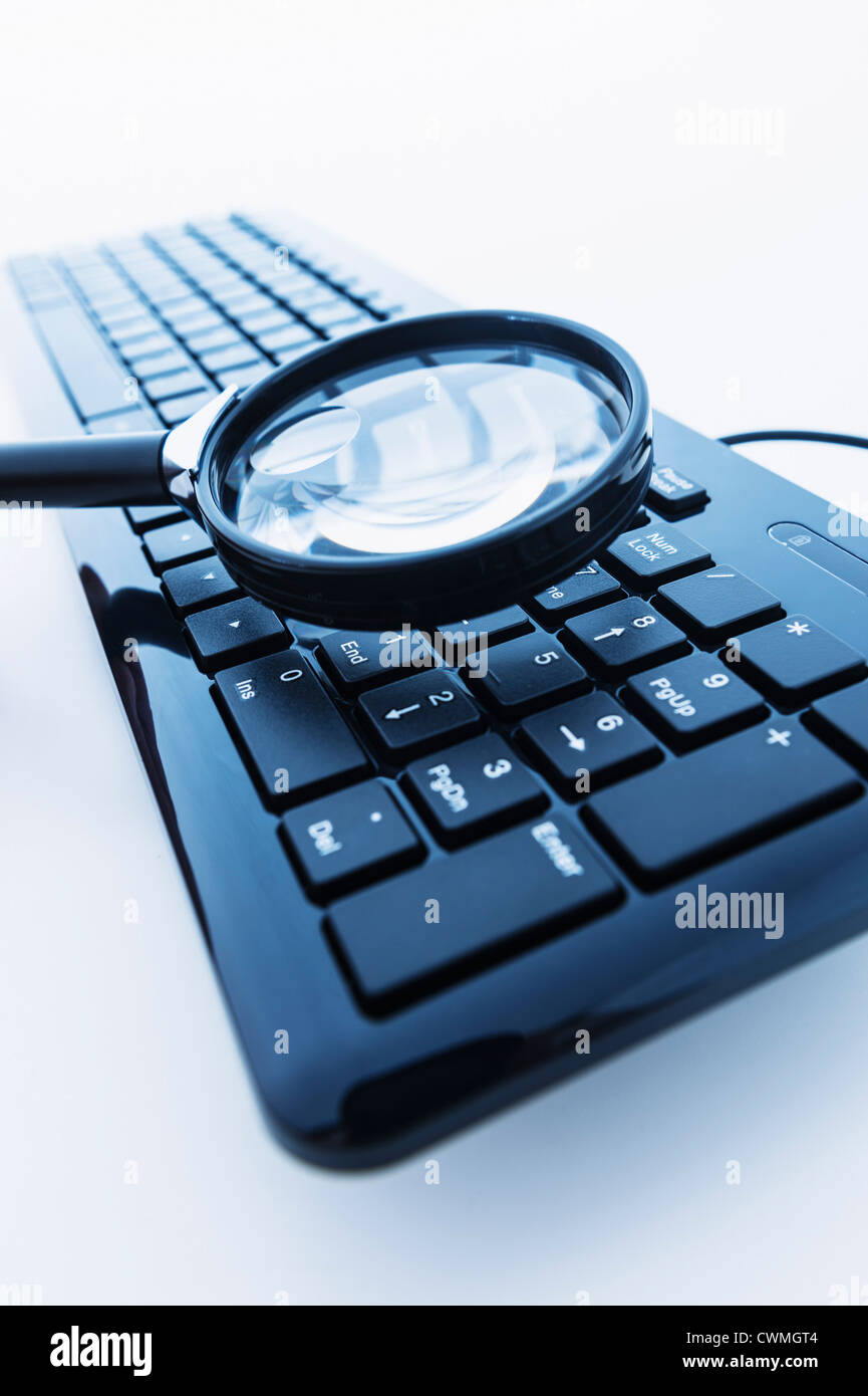 Magnifying glass over computer keyboard Stock Photo - Alamy