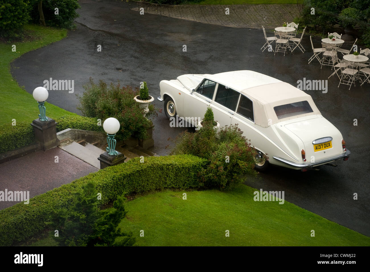 a white or cream wedding car waits in the driveway of a wedding venue ...