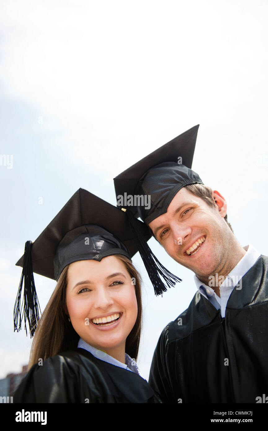 USA, New Jersey, Jersey City, Young man and woman wearing graduation ...