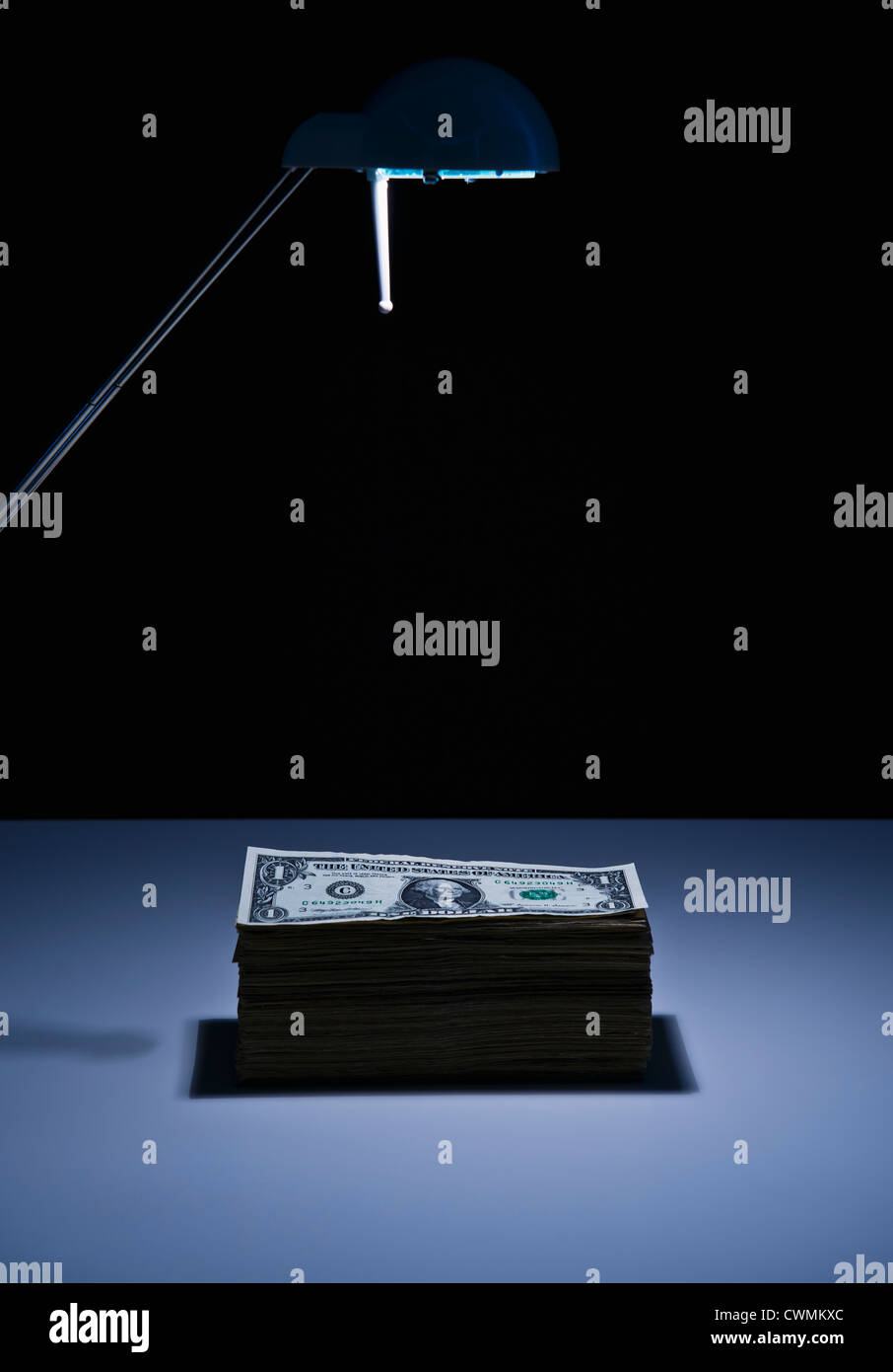 Stack of dollars under desk lamp Stock Photo - Alamy