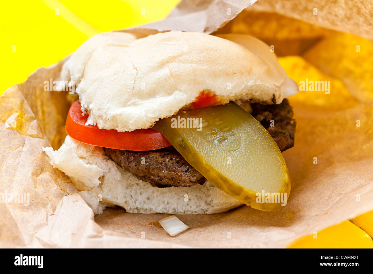 Homemade hamburger with pickle and tomato in paper wrapper Stock Photo ...