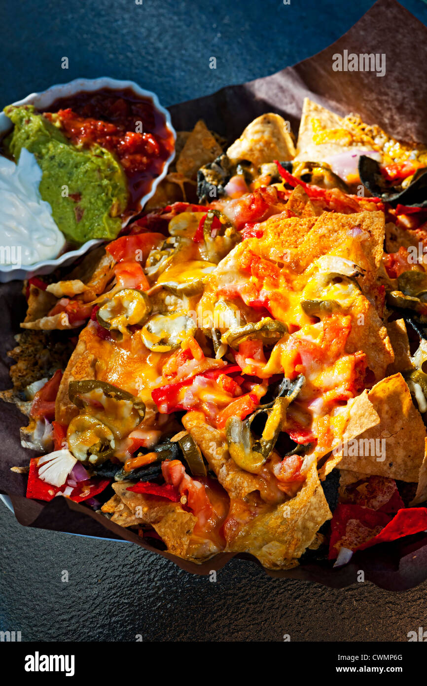 Basket of nachos with cheese jalapeno and toppings Stock Photo - Alamy