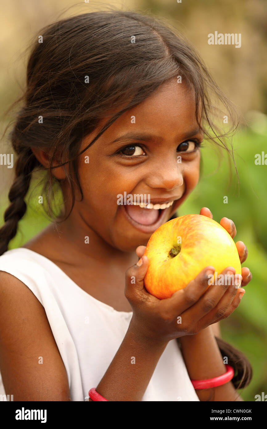 Young Indian rural girl eating an apple Andhra Pradesh South India ...