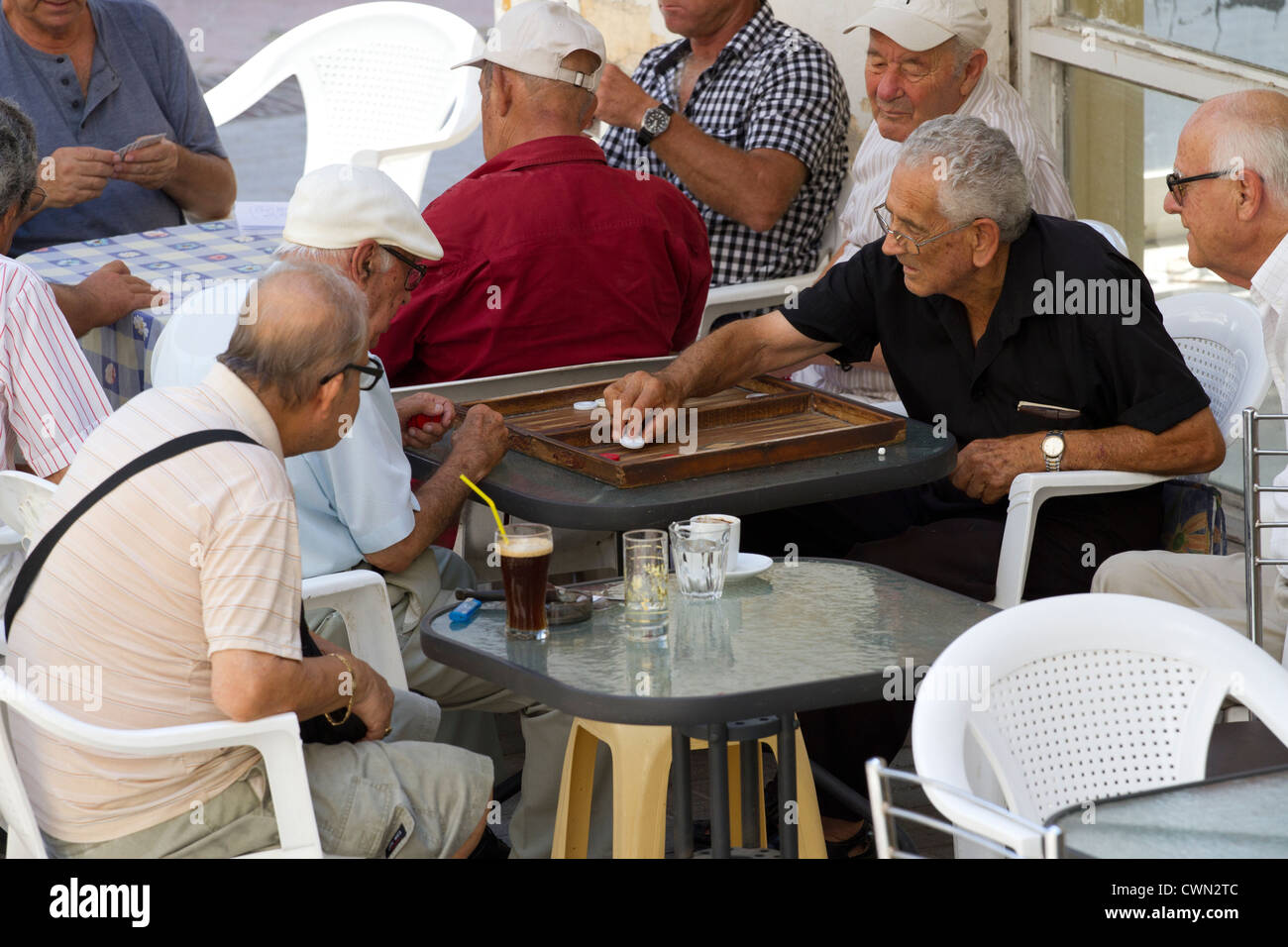 Men socialising outside a coffee bar in Rhodes town Greece playing ...