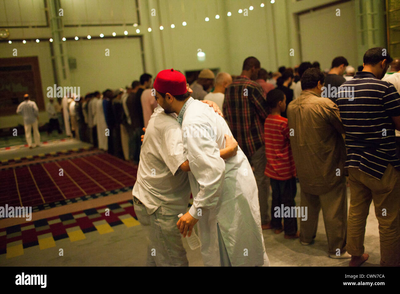 Muslim men greet each other before praying at a mosque during the month ...