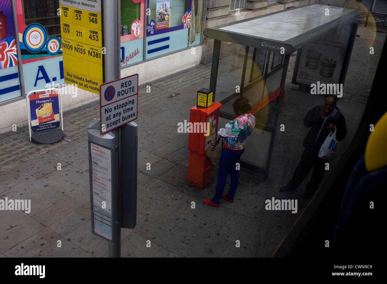 Seen through a bus window, a street sweeper rests for a cigarette ...