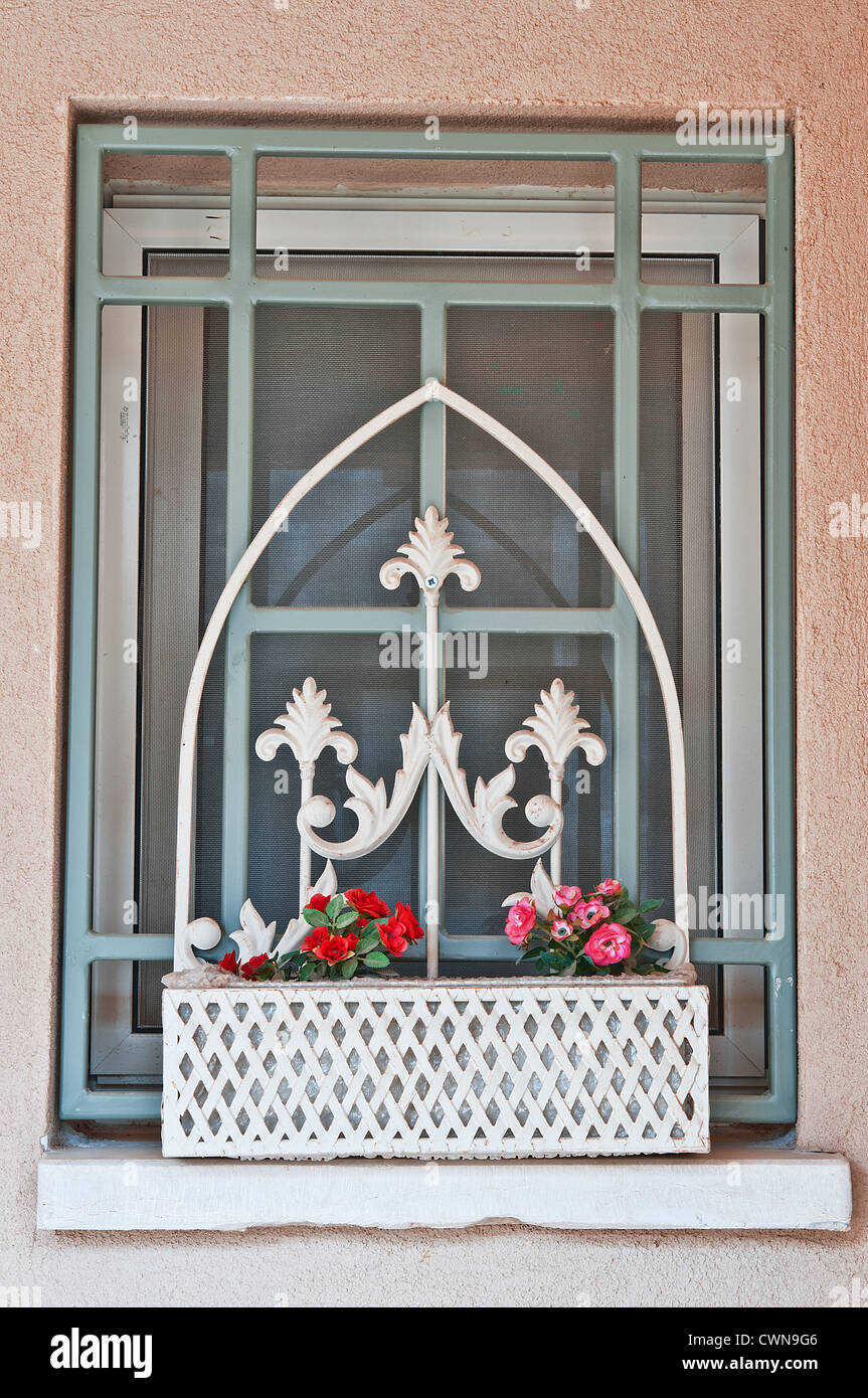 window with bars in the country house and a decorative box with flowers ...