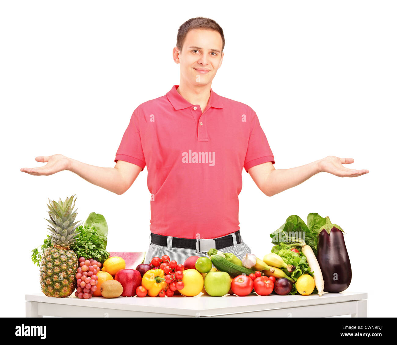 Handsome guy gesturing with his arms behind a table with fruits and ...