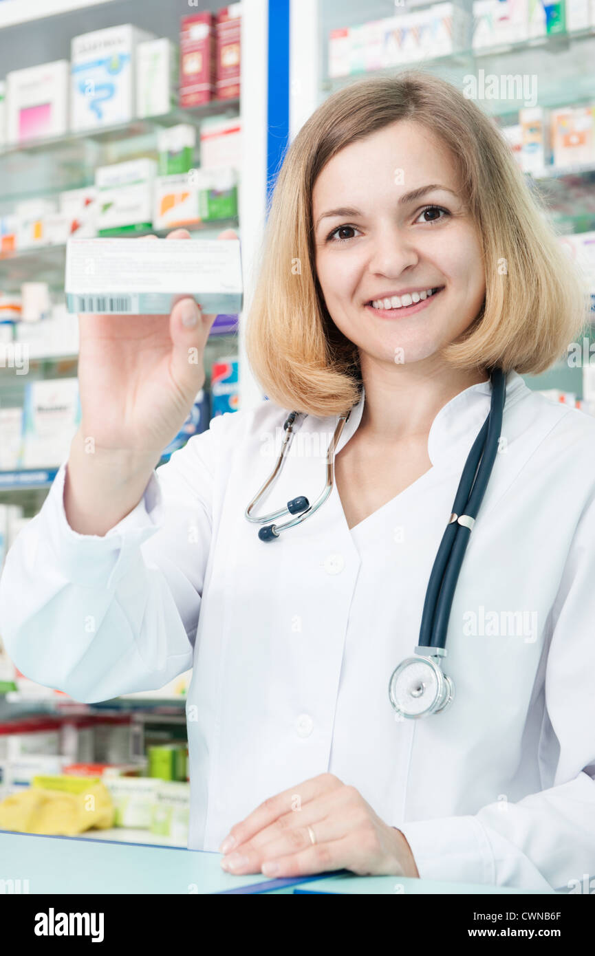 Young smiling female chemist demonstrating box with drugs Stock Photo ...