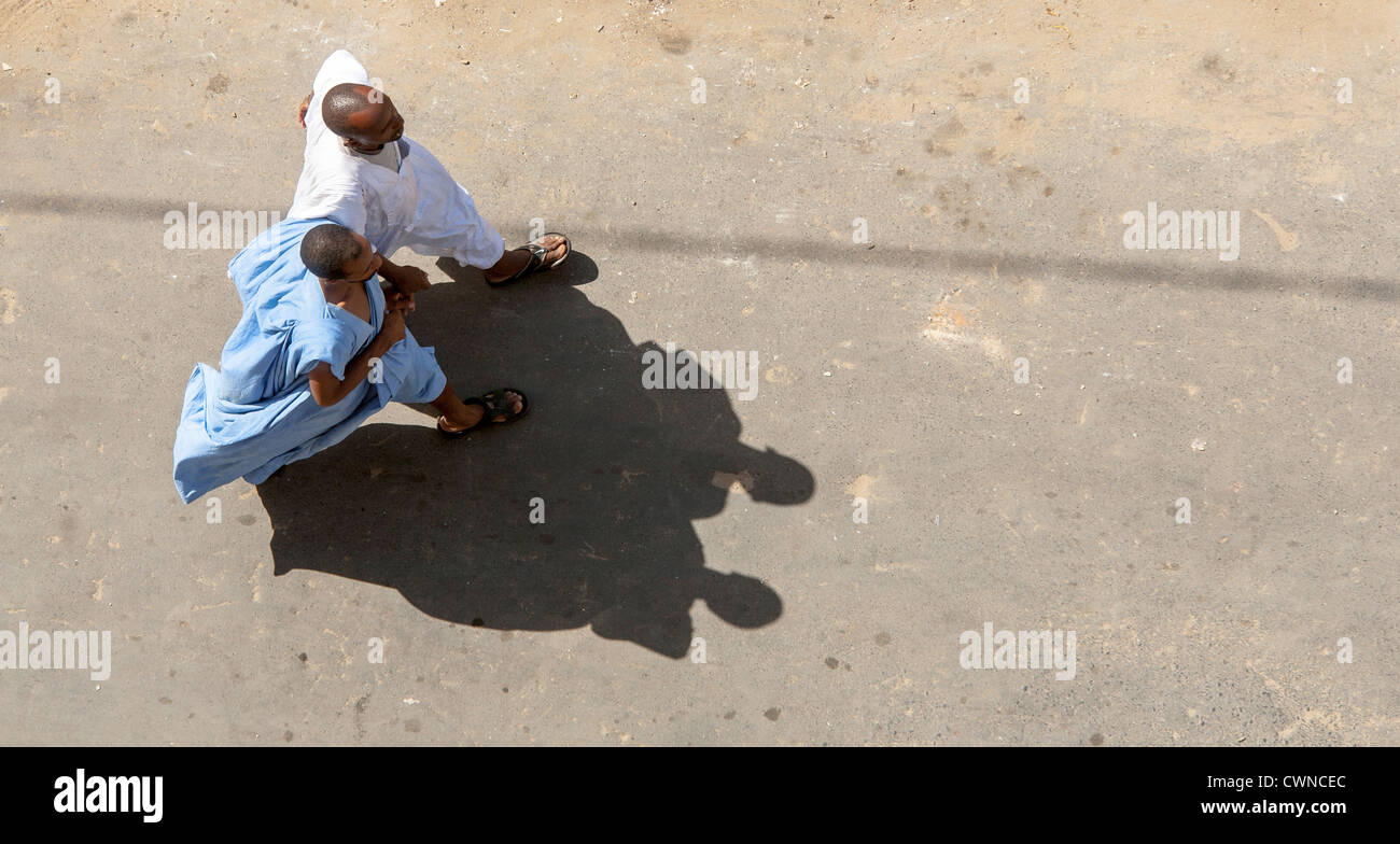 Two men wearing traditional Mauritanian blue and white robes, walking ...