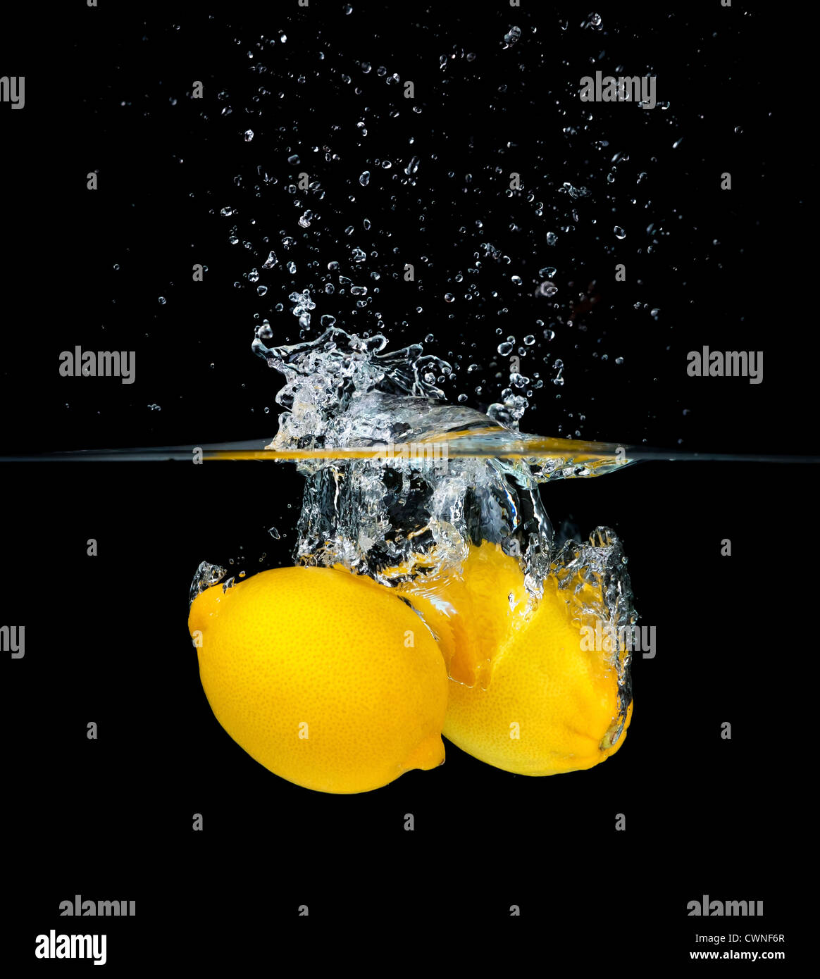 Two fresh lemons falling into water, isolated on black background Stock ...