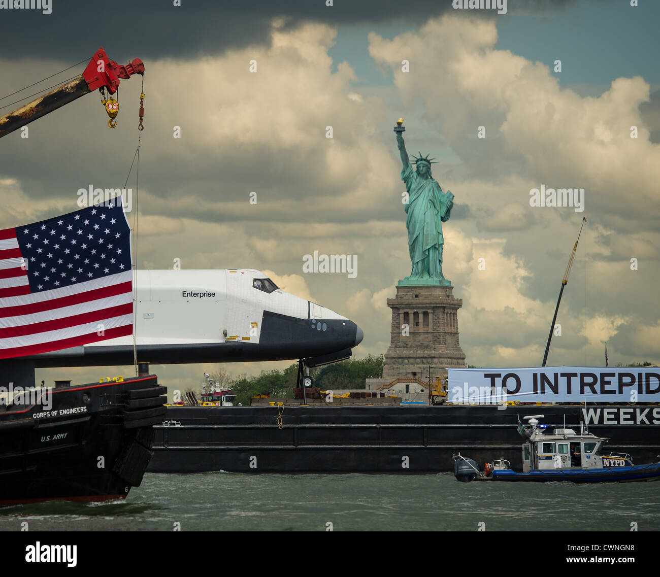 The space shuttle Enterprise, atop a barge, passes the Statue of ...