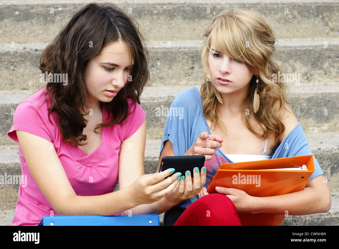Two young women looking mad over some text received on their cell phone ...