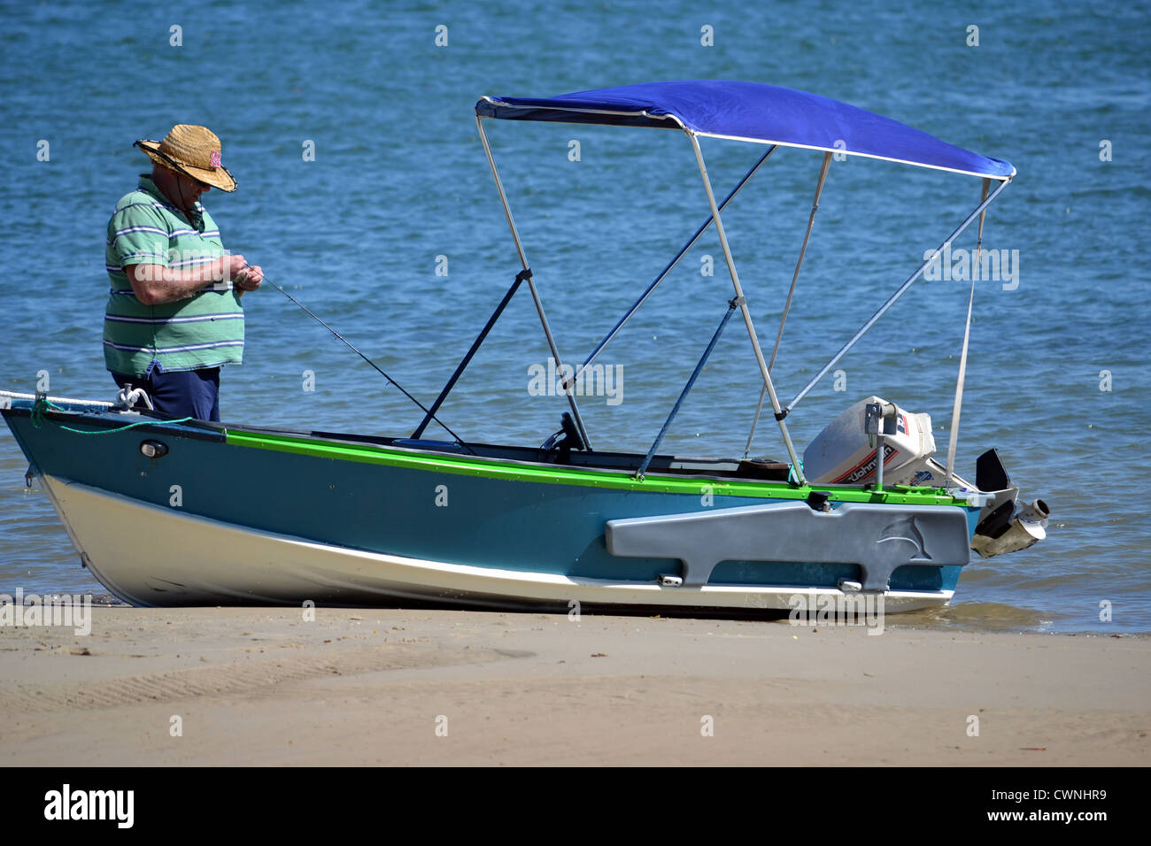Man on beach with boat getting ready to go fishing Stock Photo - Alamy