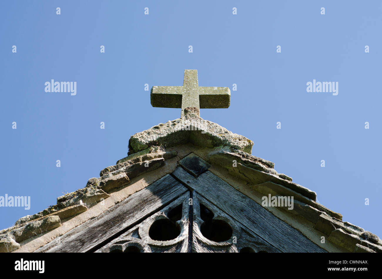 A stone cross on the apex of an old church entrance porch, decoratively ...