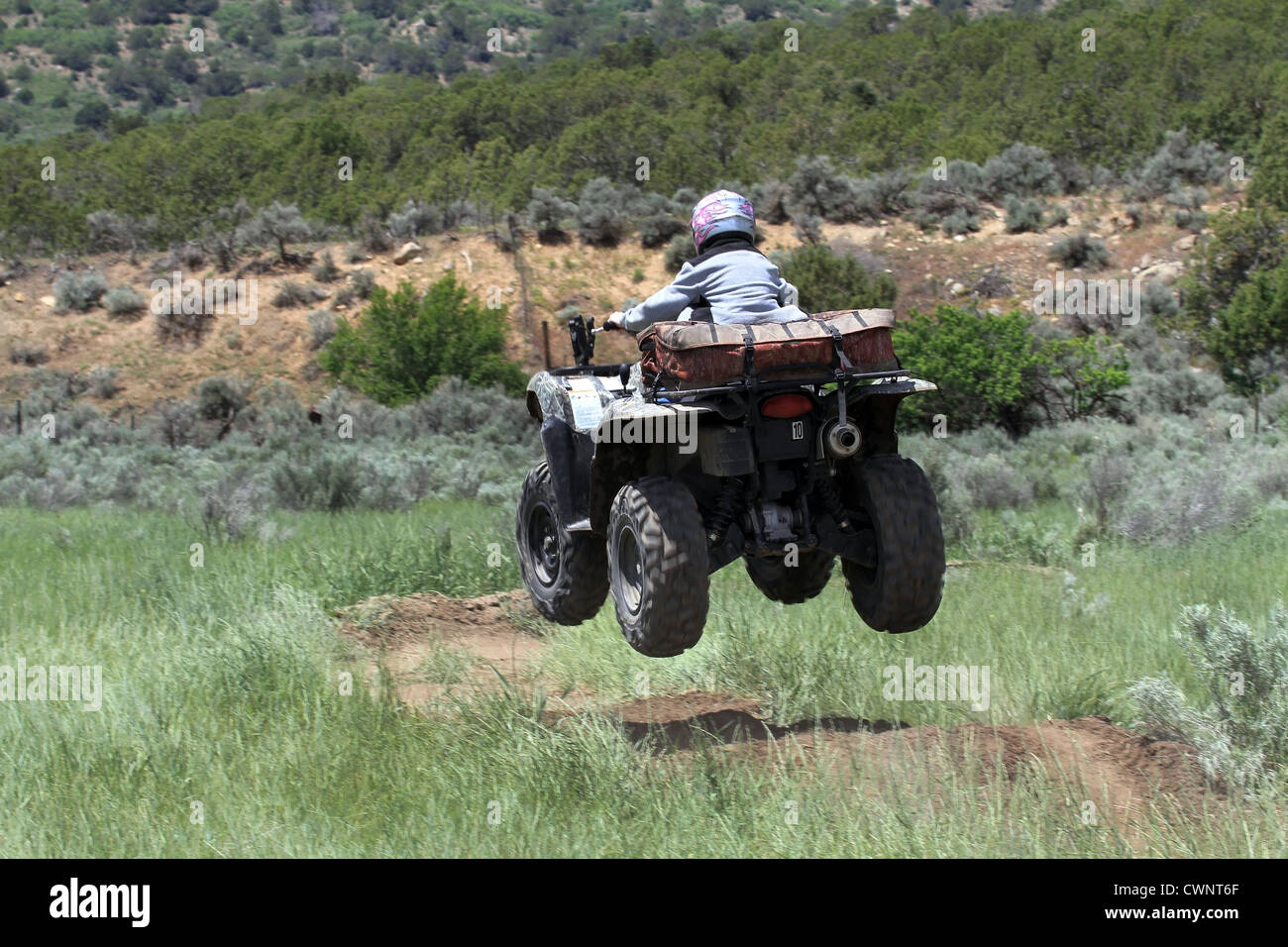 Motorcycle ATV ride on rough dirt track by man.Jumps over earth ramps ...