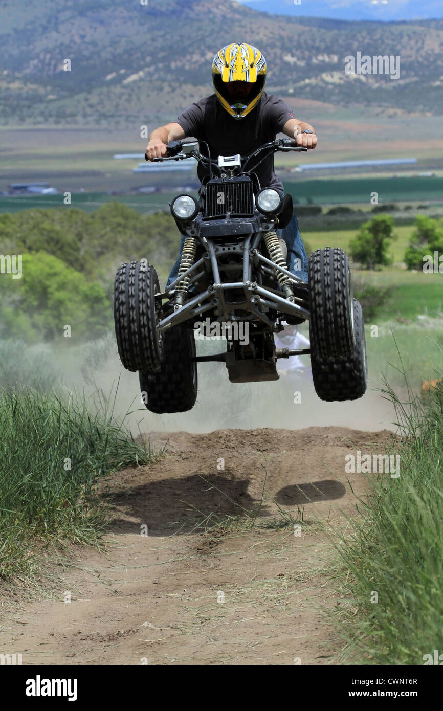 Motorcycle ATV ride on rough dirt track by man.Jumps over earth ramps ...