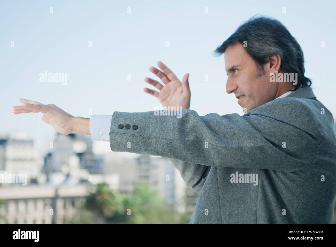 Mature businessman holding arms out in front of him and pointing ...