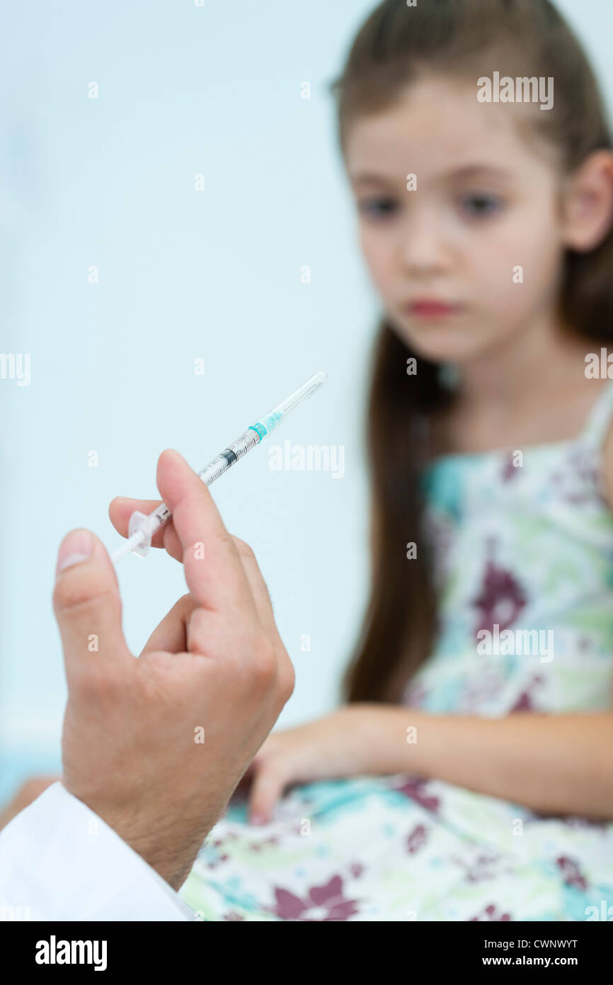 Doctor's hand holding syringe, girl sitting in background Stock Photo ...