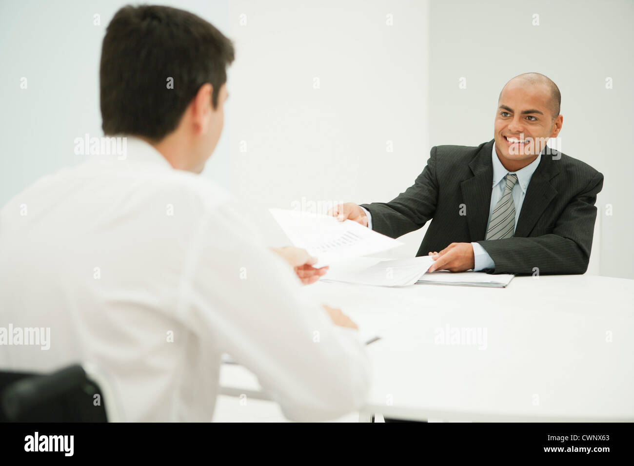 Businessmen discussing documents in meeting Stock Photo - Alamy