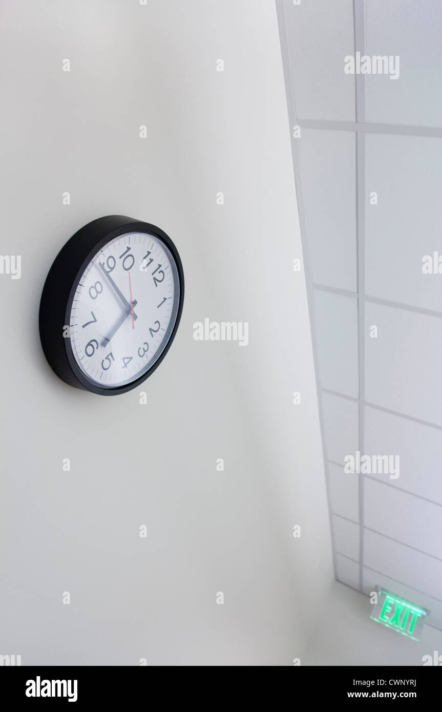 Wall clock and exit sign in office Stock Photo - Alamy